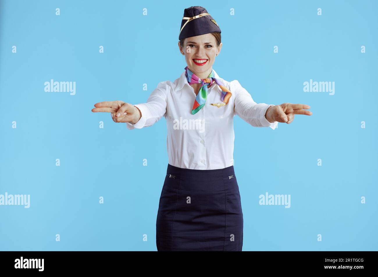 smiling stylish female stewardess against blue background in uniform ...