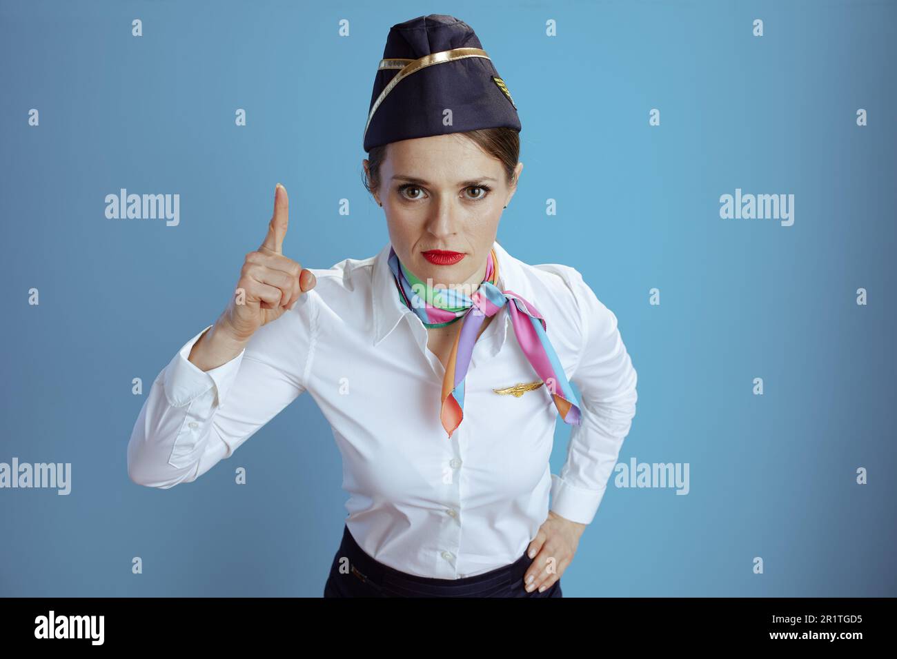 modern female stewardess against blue background in uniform with raised ...