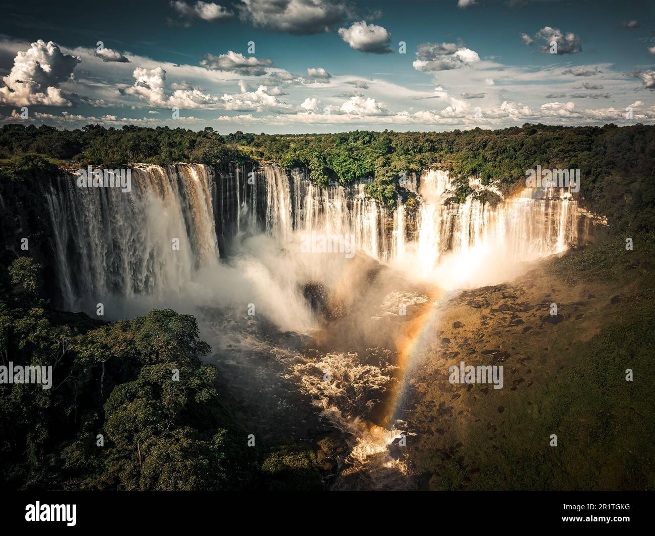 A stunning landscape of Kalandula Falls in Angola, featuring a vibrant, multi-colored rainbow ...
