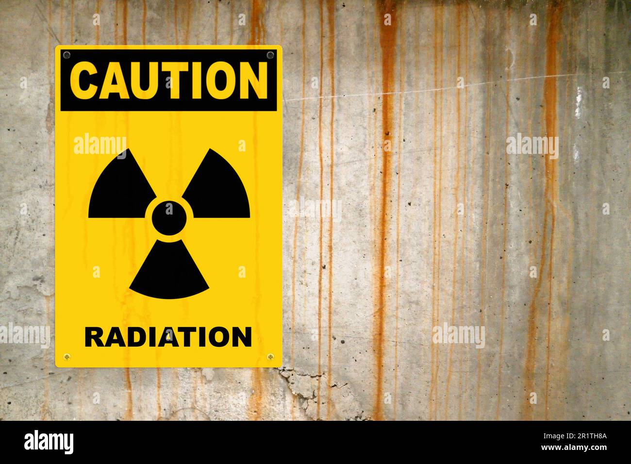 Yellow warning sign screwed to a concrete wall to warn about a threat ...