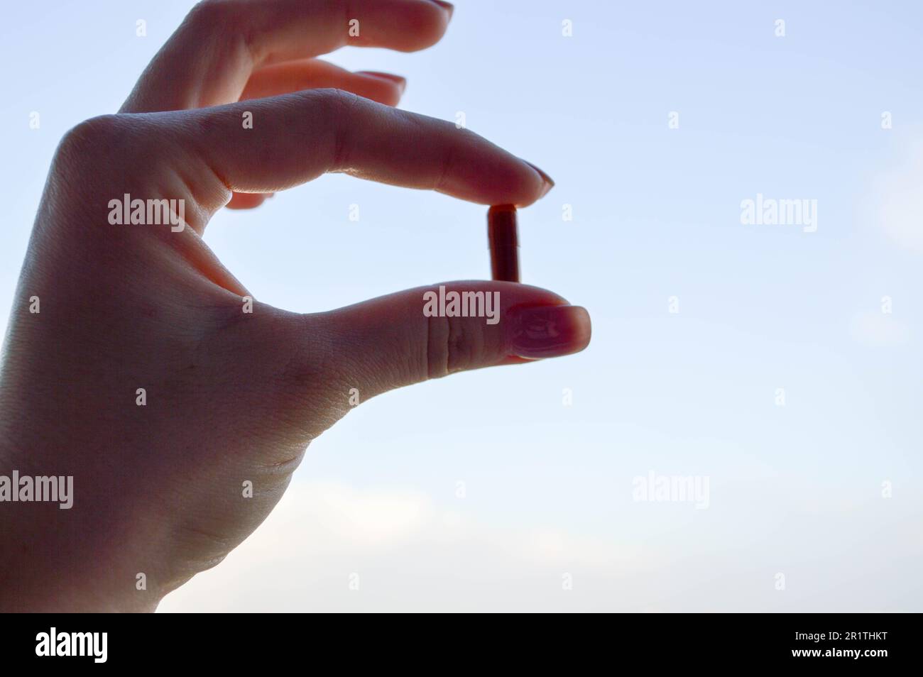 A brown oval-shaped tablet is squeezed in the hands of a girl with ...