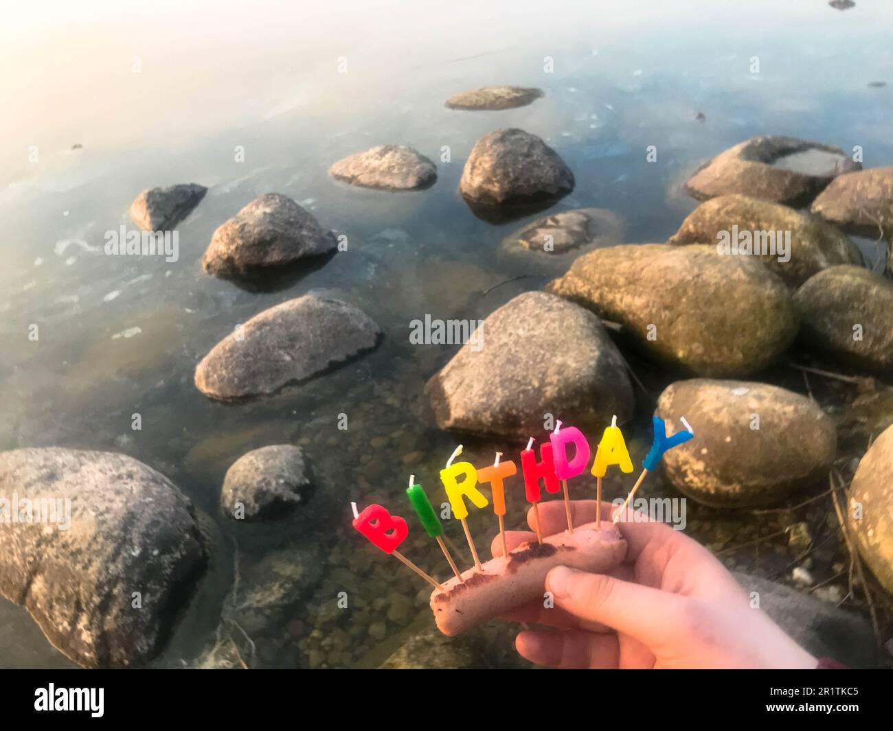 Happy birthday inscription made of holiday candles in the hands of a ...