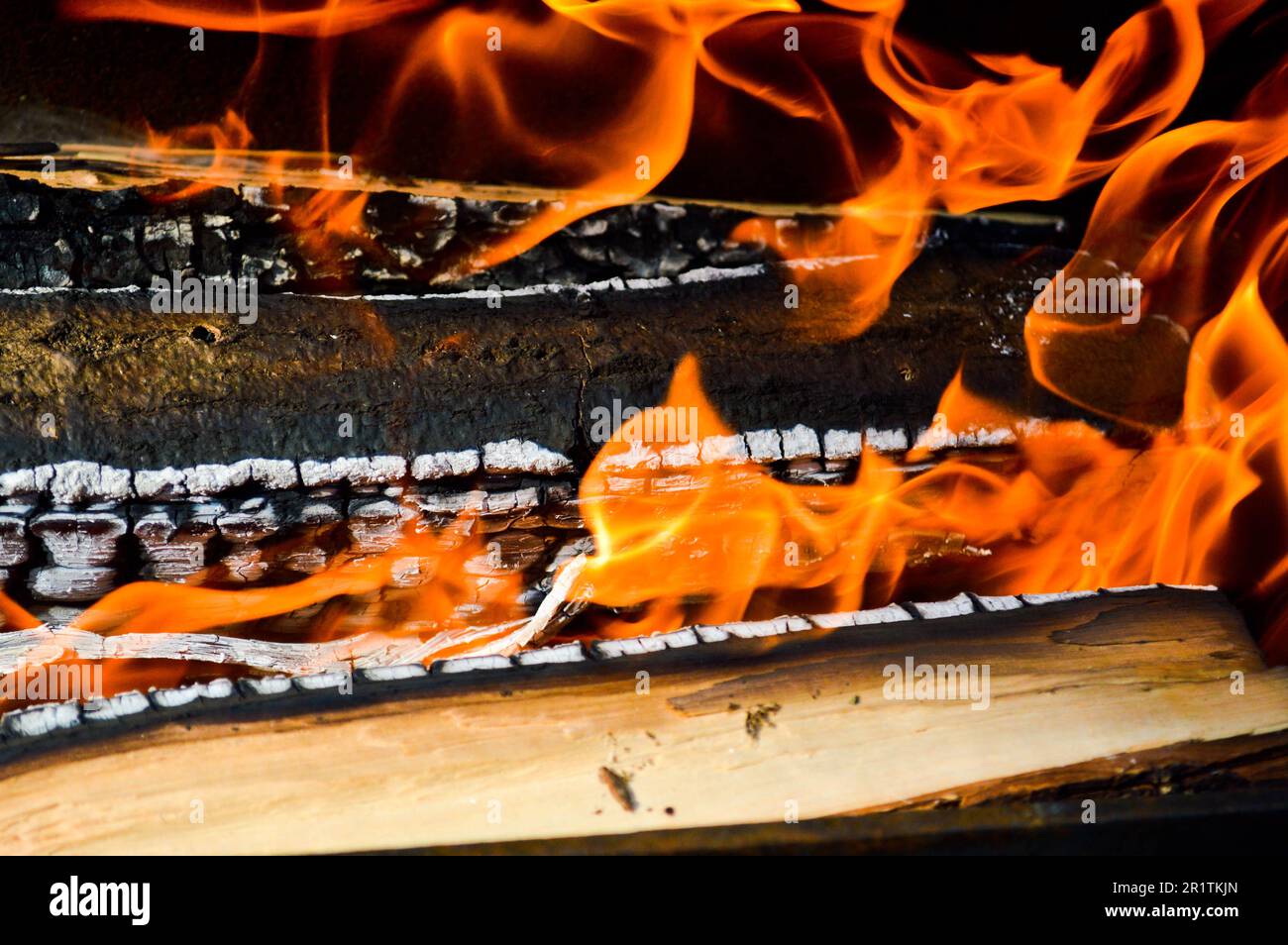 Wooden burning hot charred planks of wood logs in a fire with tongues ...