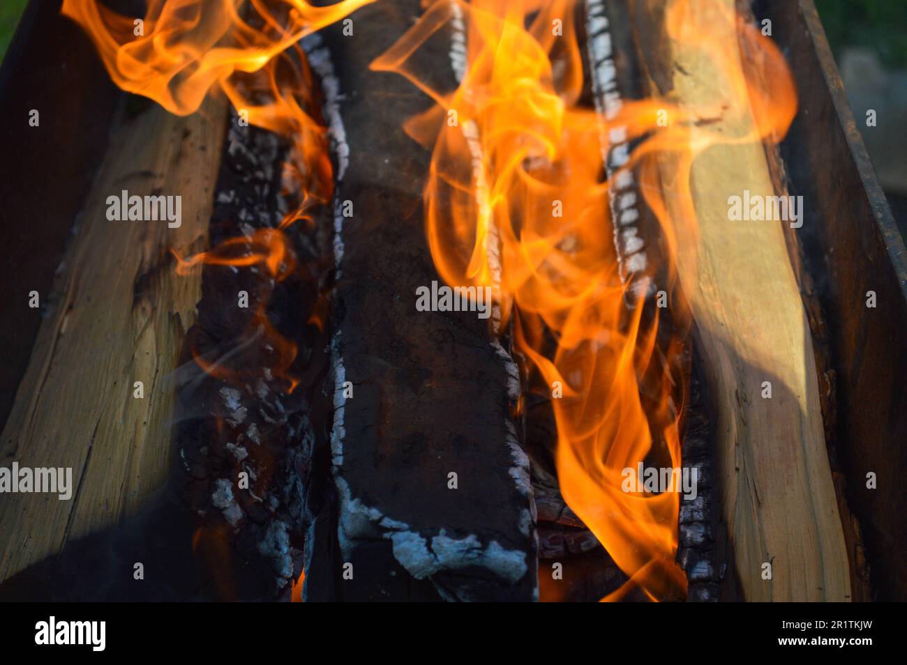 Wooden burning hot charred planks of wood logs in a fire with tongues ...