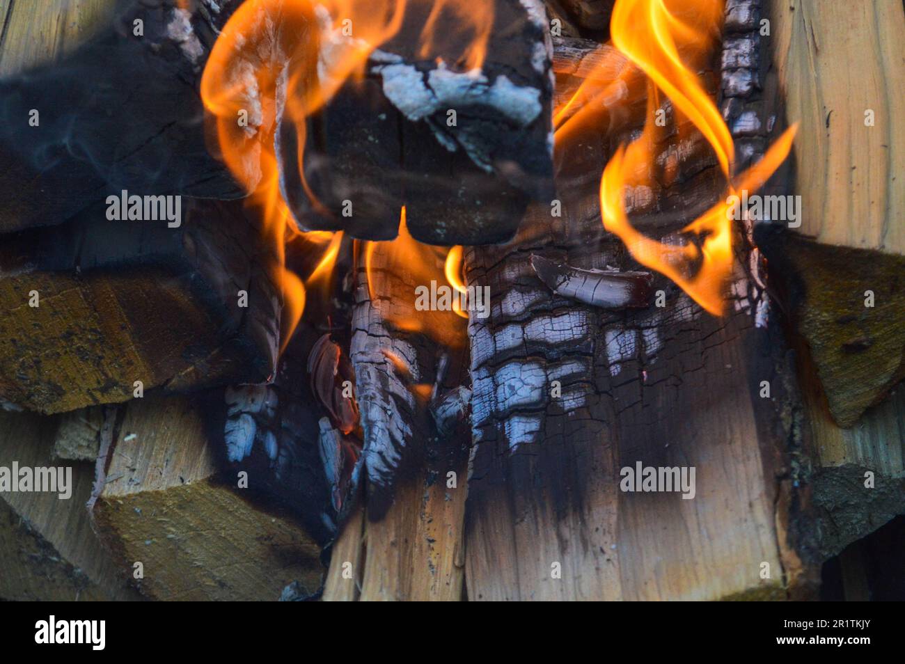 Wooden burning hot charred planks of wood logs in a fire with tongues ...