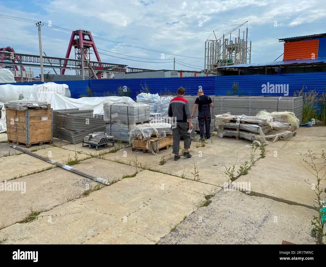 Male workers walk through a warehouse of industrial equipment and ...