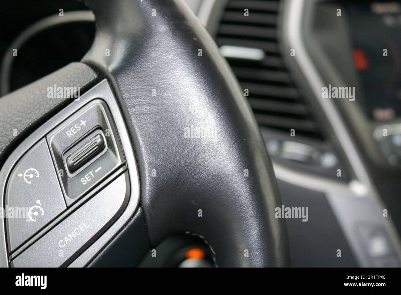 Cruise control buttons on the black leather steering wheel of the car ...