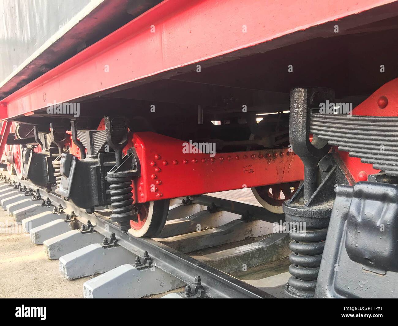 Large iron wheels of a red and black train standing on rails and ...