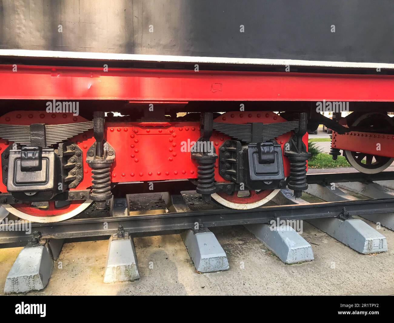Large iron wheels of a red and black train standing on rails and ...