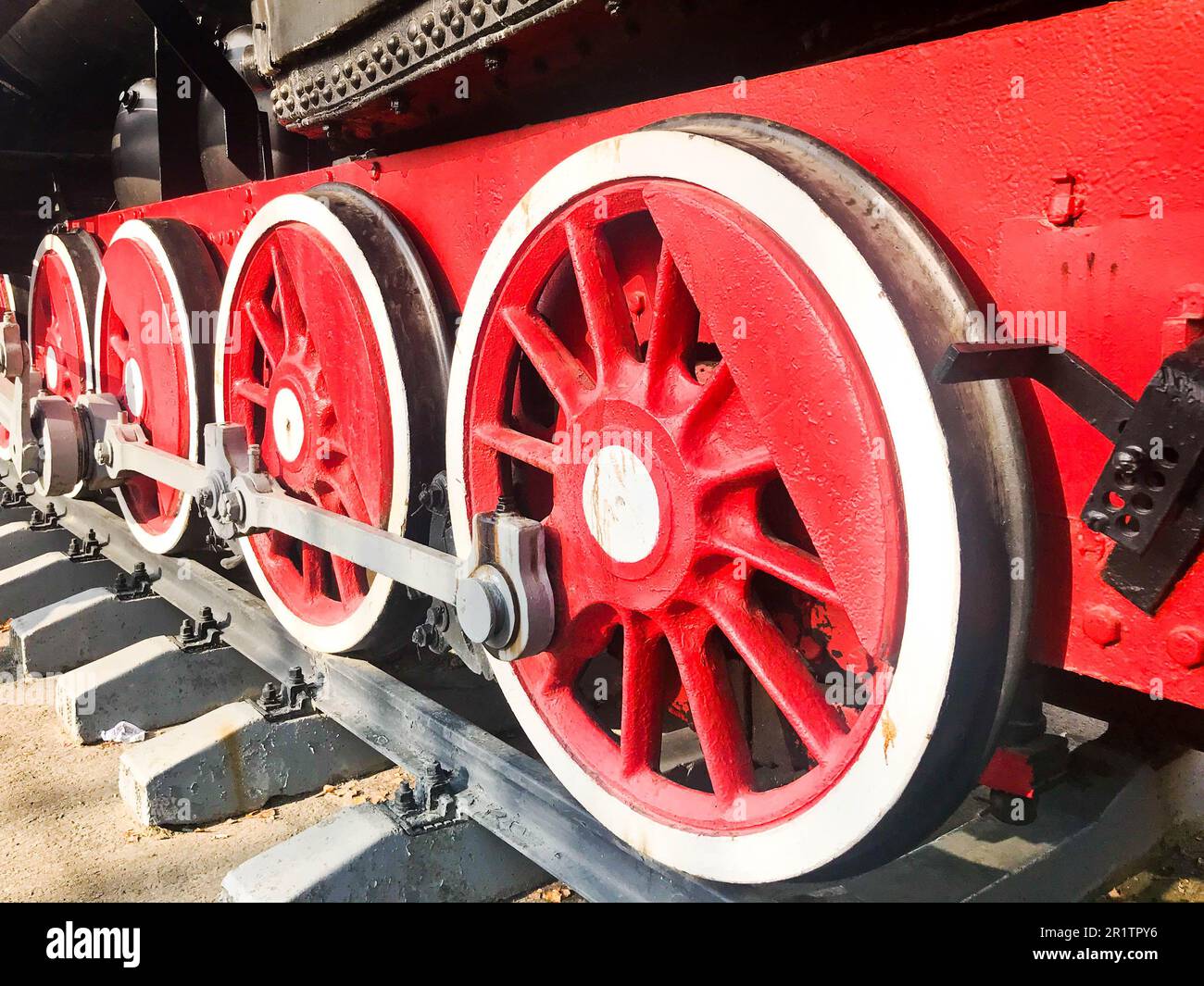 Large iron wheels of a red and black train standing on rails and ...