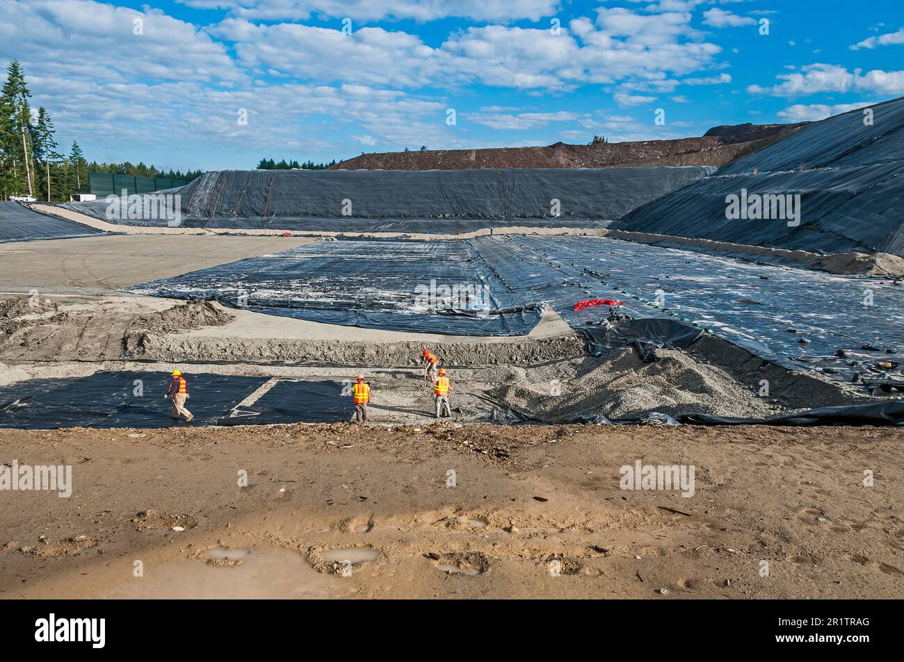 Workers endeavor to install some geomembranes in an active solid waste ...