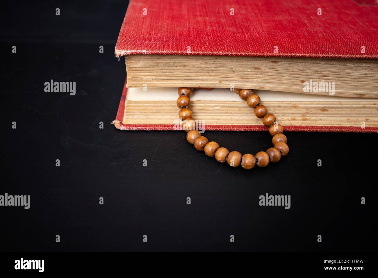 Wooden beads on a string between the pages of a red hard cover book ...