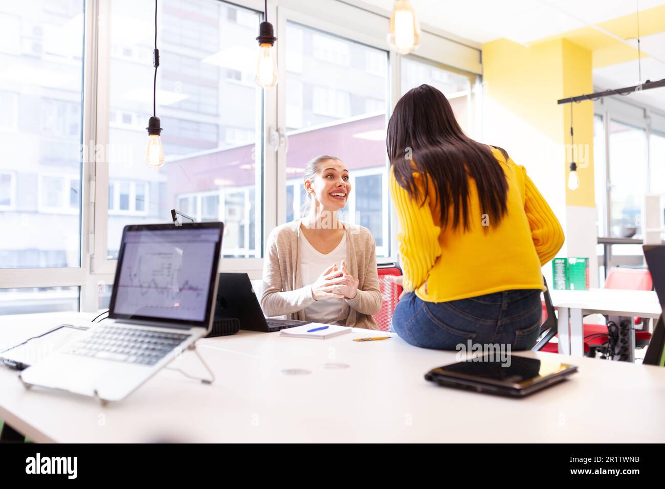 Female friends in an office. Business colleagues gossiping at work ...