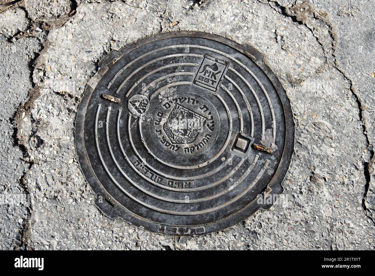 A manhole cover outside the Jerusalem Old City with Hebrew writing ...