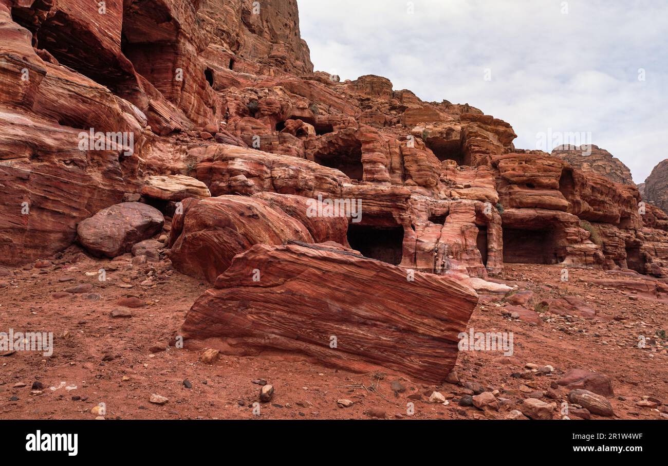 Simple dwelling ruins - cave like holes in stone wall, cloudy sky above ...