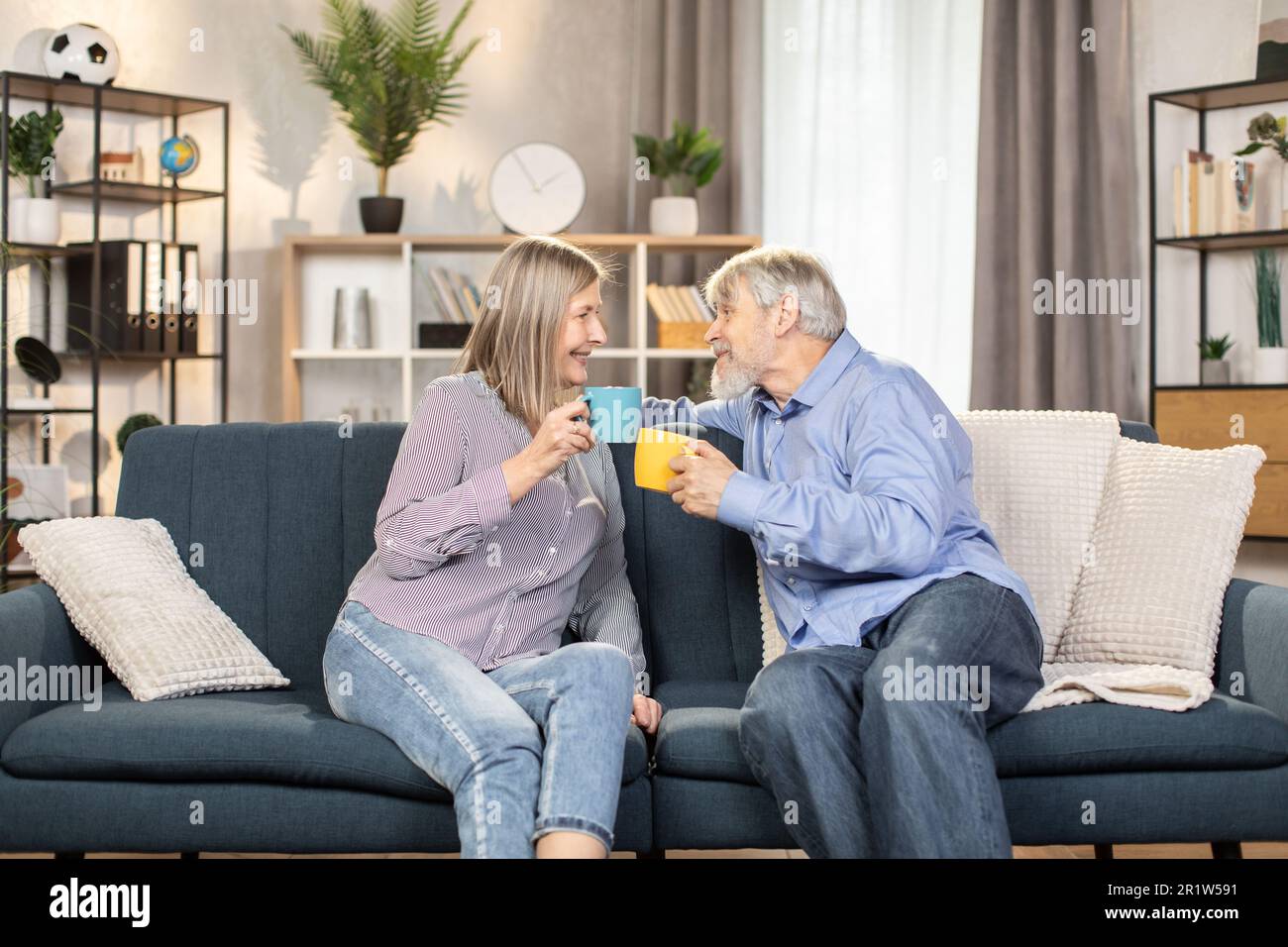 Carefree mature couple in everyday clothes enjoying morning coffee ...