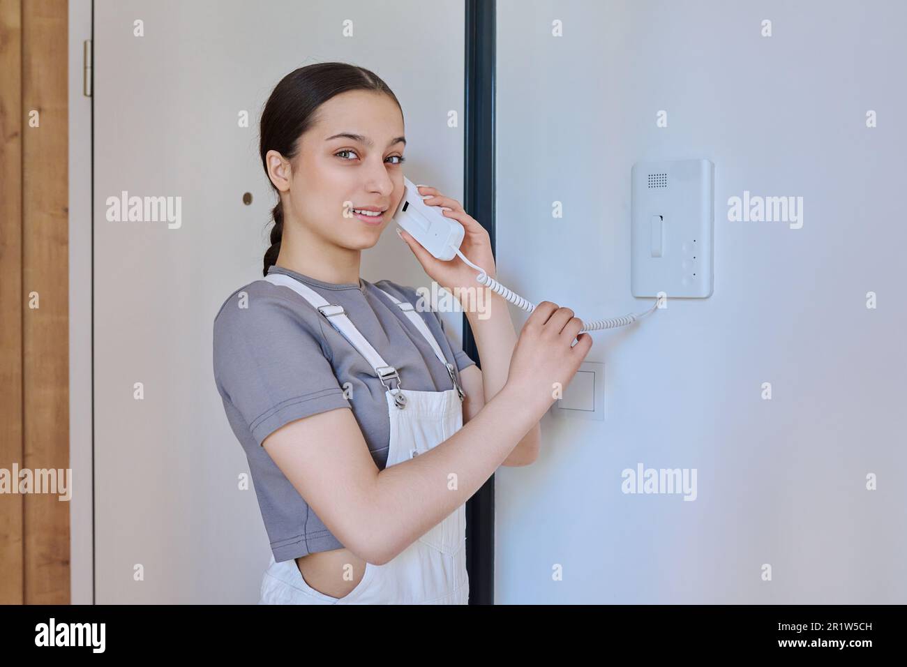 Teenage girl holding intercom handset while talking to guest Stock ...