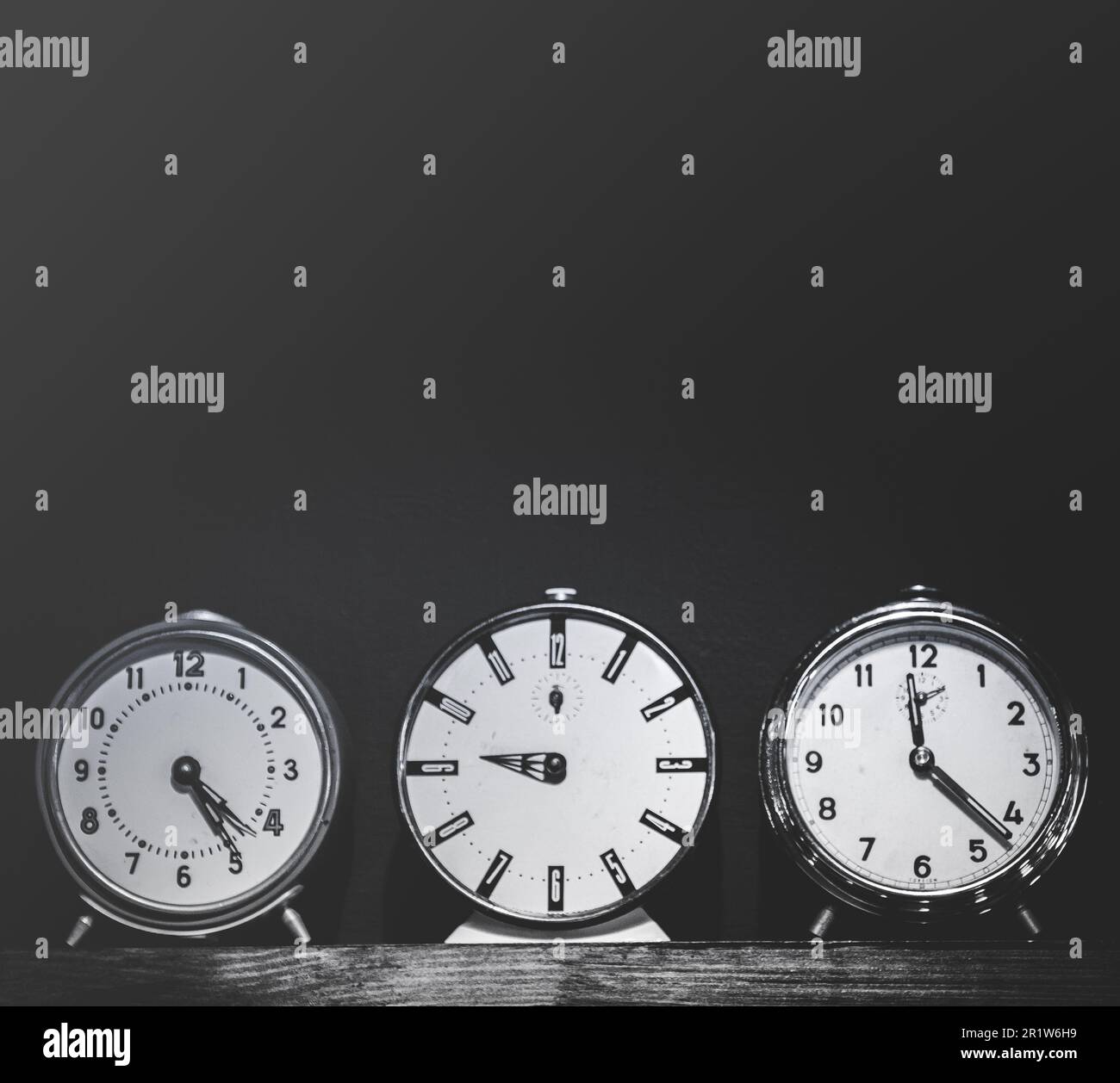 A black and white image of three classic circle-shaped analog clocks ...