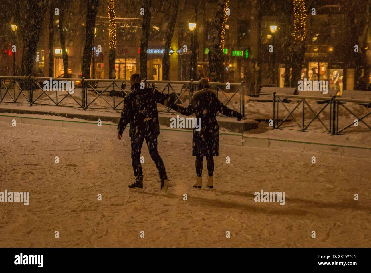Couple two people holding hands are ice skating in winter in the ...