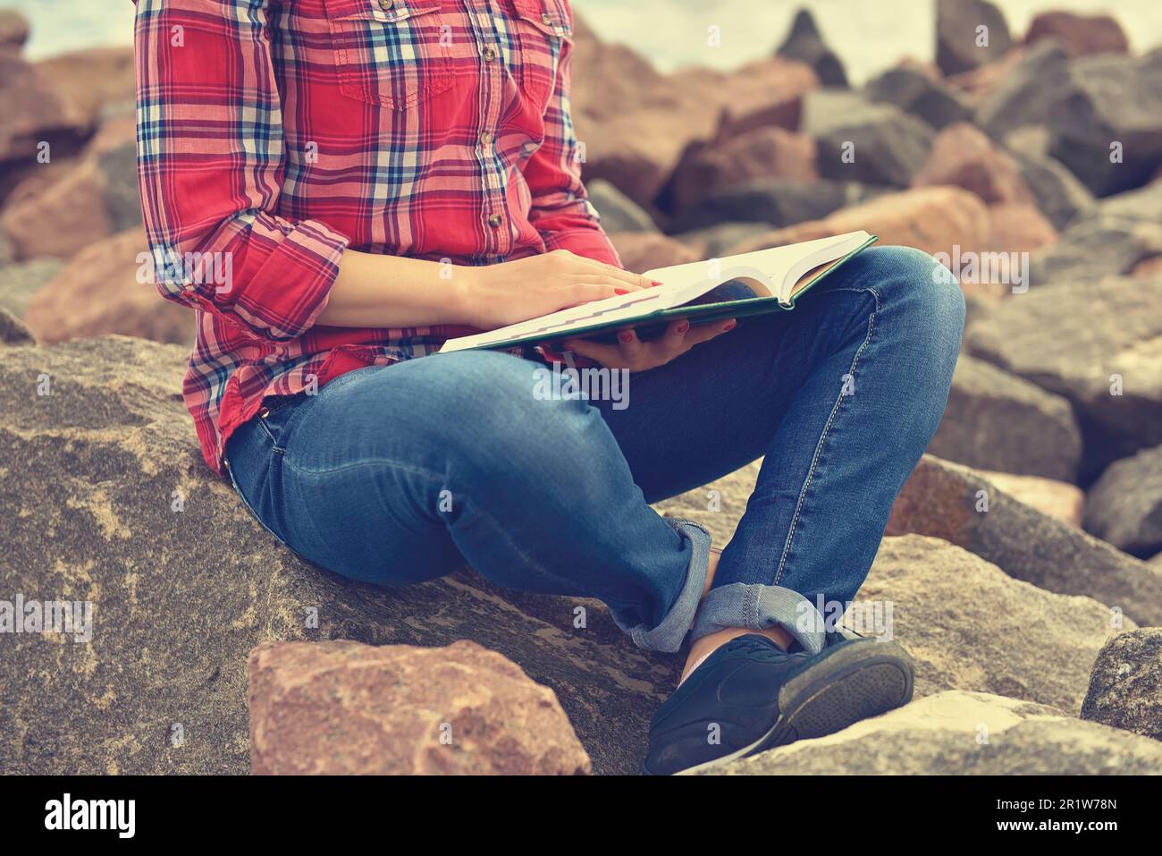 girl sitting on rock and reading a book. Vintage photo Stock Photo - Alamy