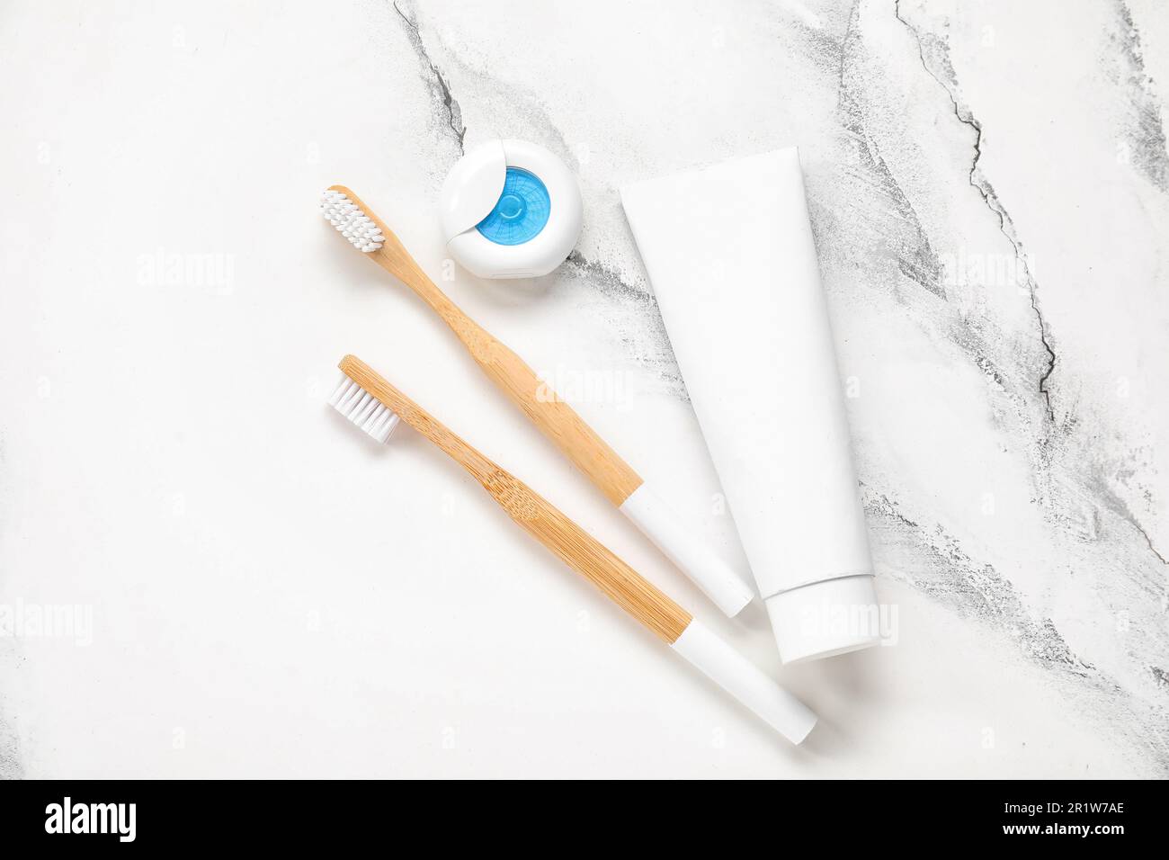 Dental floss, paste and bamboo toothbrush on white marble background ...
