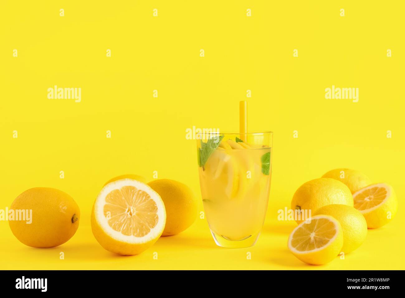 Glass with fresh lemonade and lemons on yellow background Stock Photo ...