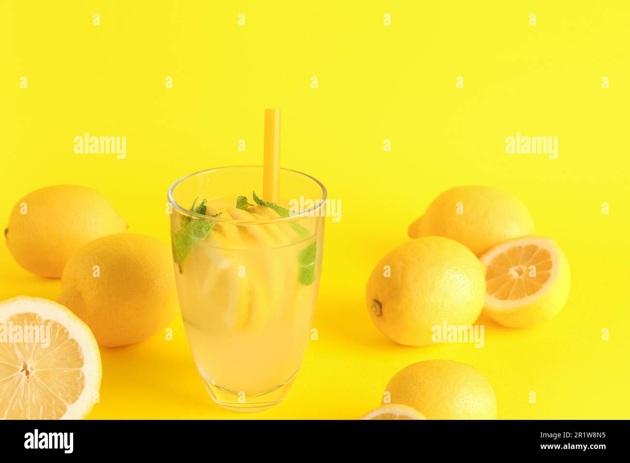 Glass with fresh lemonade and lemons on yellow background Stock Photo ...