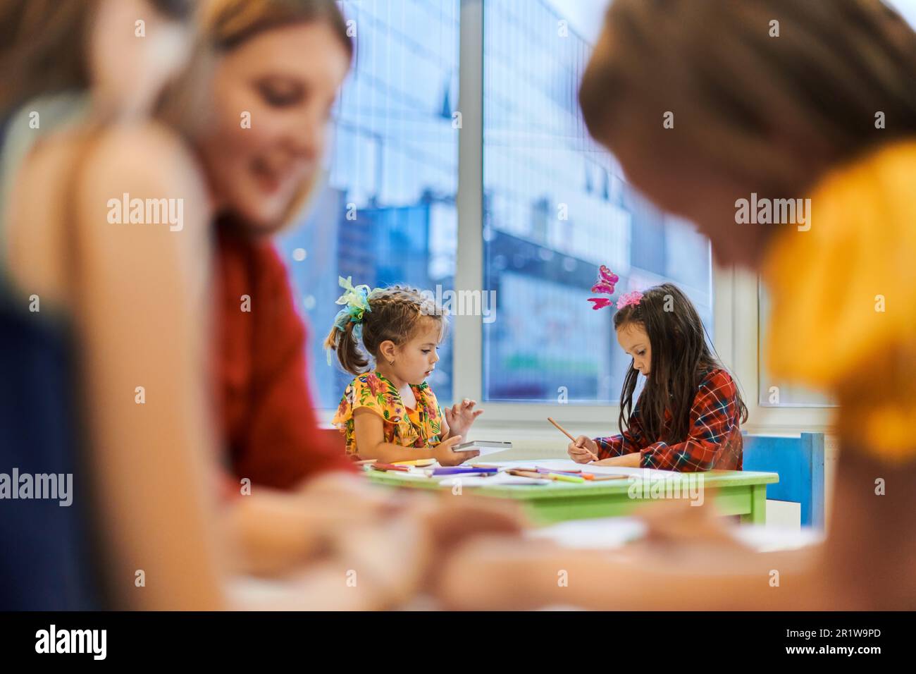 Creative kids during an art class in a daycare center or elementary school classroom drawing ...