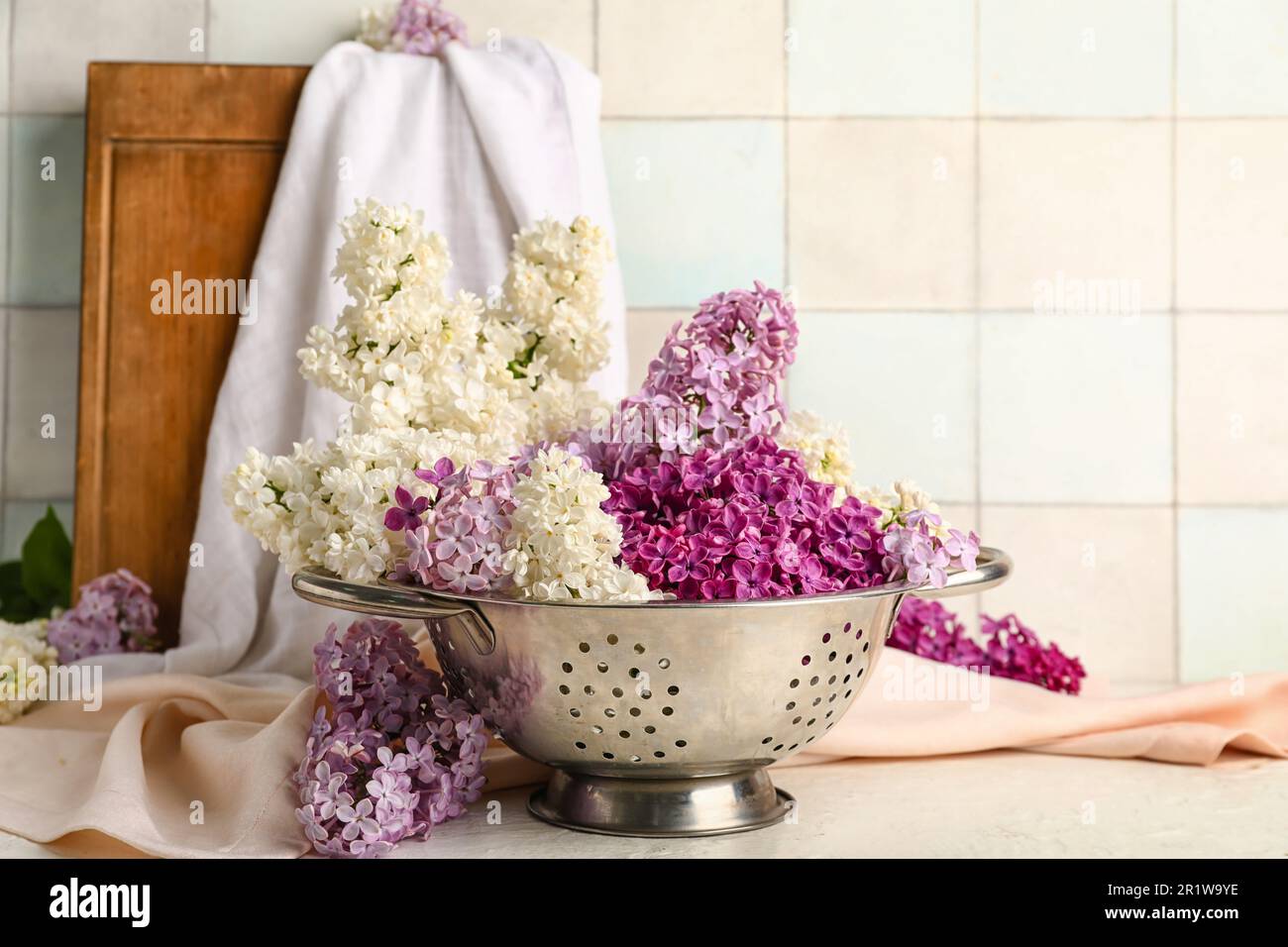 Colander with Beautiful fragrant lilac flowers near white tile Stock ...