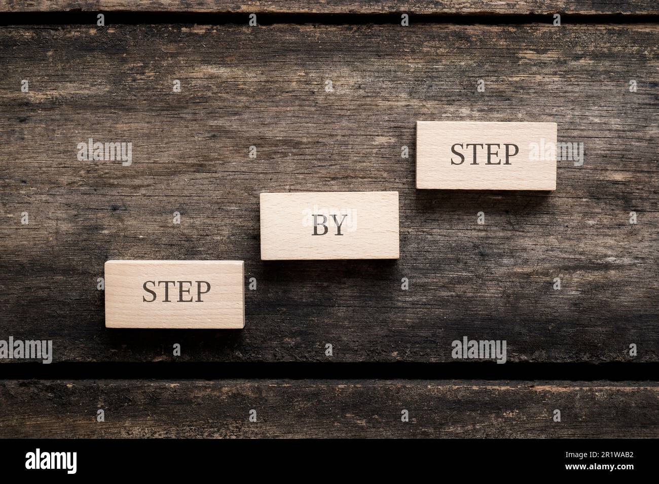 Three wooden pegs with a step by step sign placed in a staircase like ...