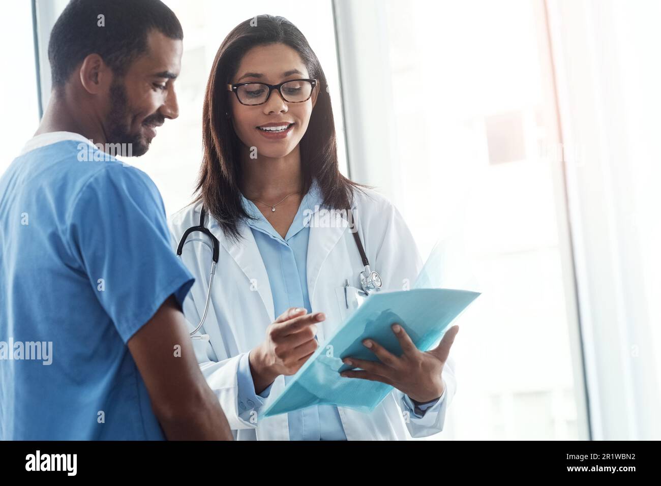 Medical teamwork at its best. two young doctors discussing the contents ...
