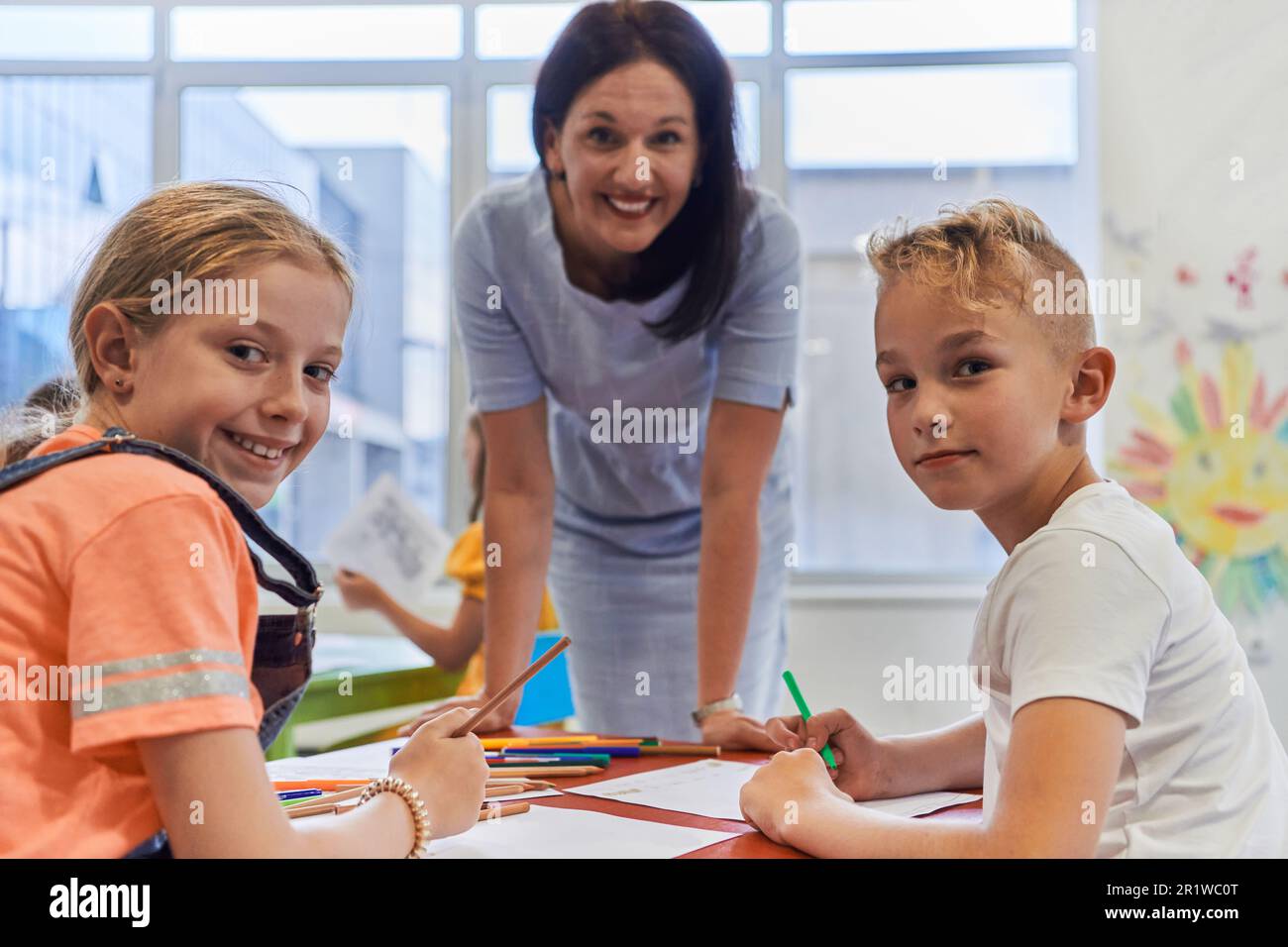 Creative kids during an art class in a daycare center or elementary school classroom drawing ...