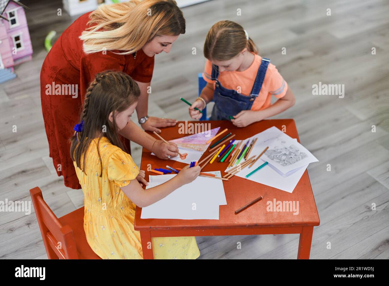Creative kids during an art class in a daycare center or elementary school classroom drawing ...