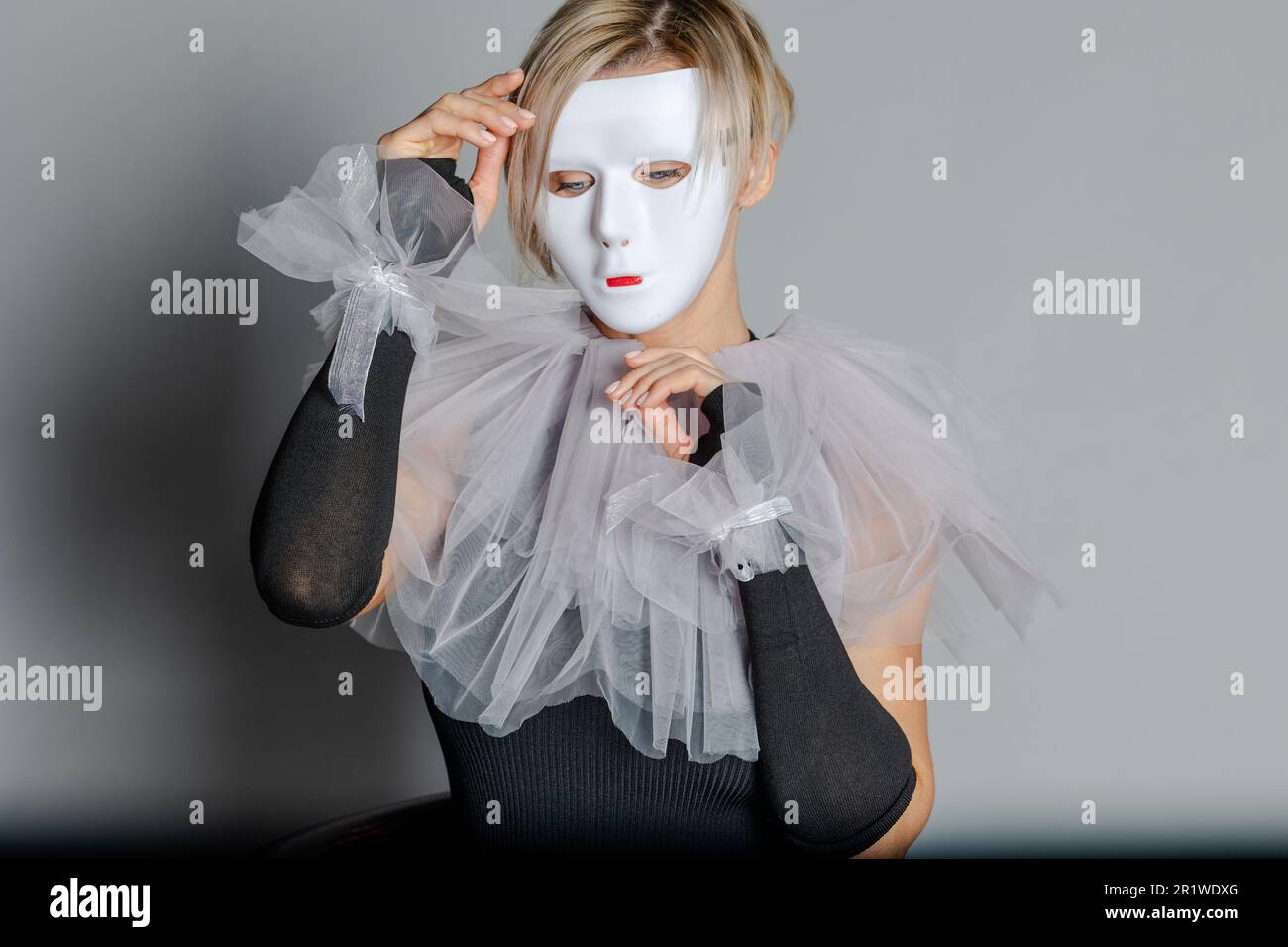 Face behind mask. Woman in white theater mask and harlequin collar on ...