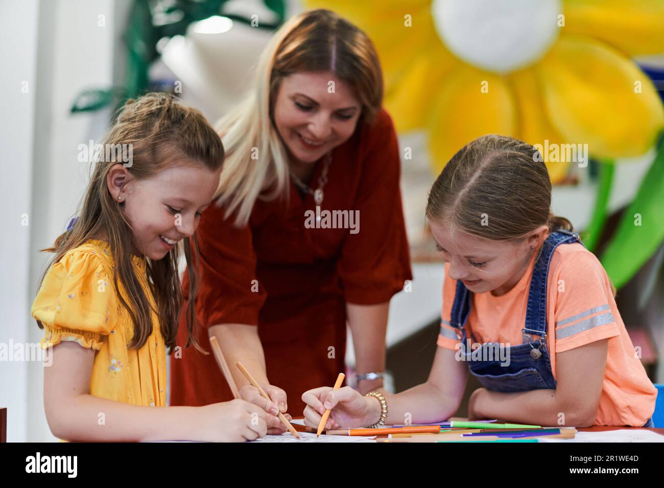 Creative kids during an art class in a daycare center or elementary school classroom drawing ...