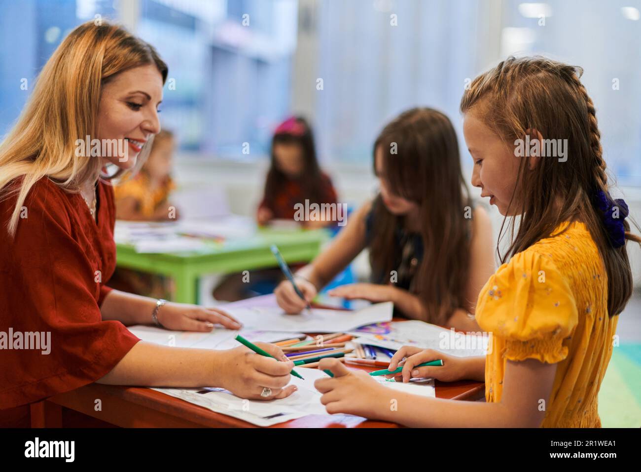 Creative kids during an art class in a daycare center or elementary school classroom drawing ...