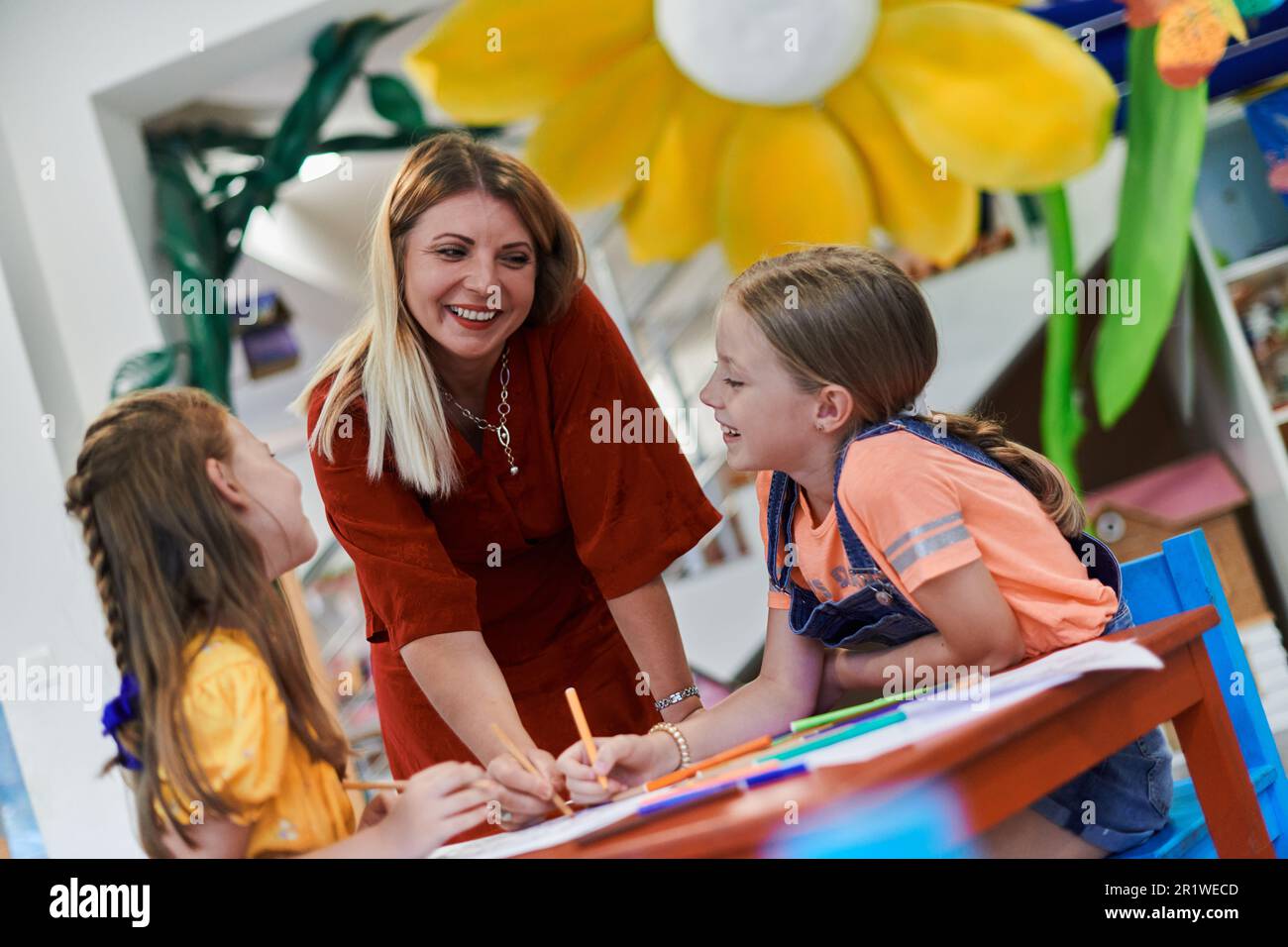 Creative kids during an art class in a daycare center or elementary school classroom drawing ...