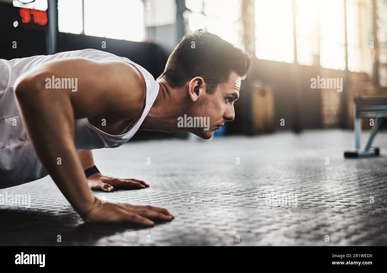 Fitness belongs to the focused. a young man doing pushups in a gym ...
