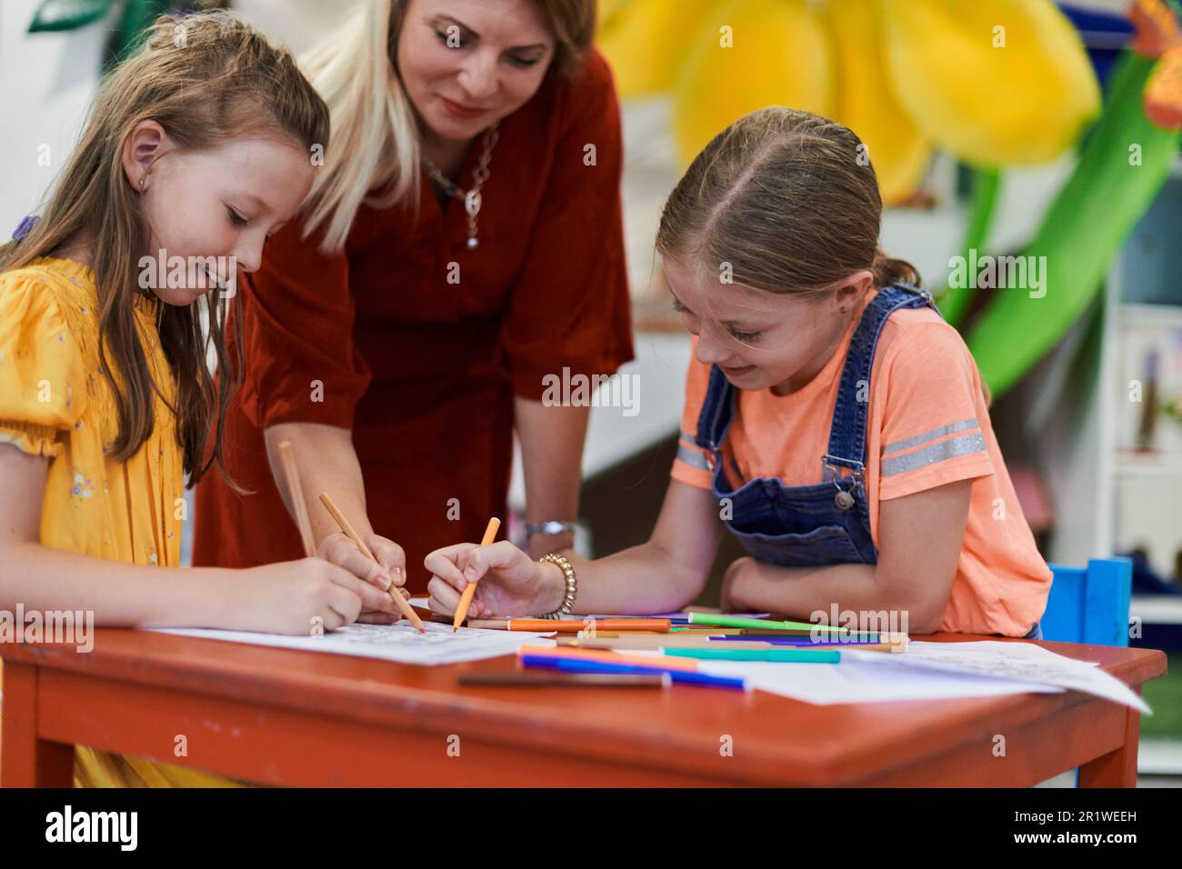 Creative kids during an art class in a daycare center or elementary school classroom drawing ...