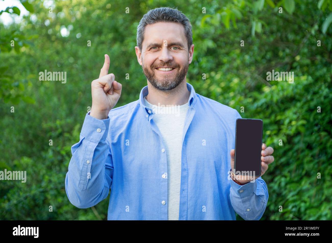 photo of inspired man presenting smartphone. man presenting smartphone ...