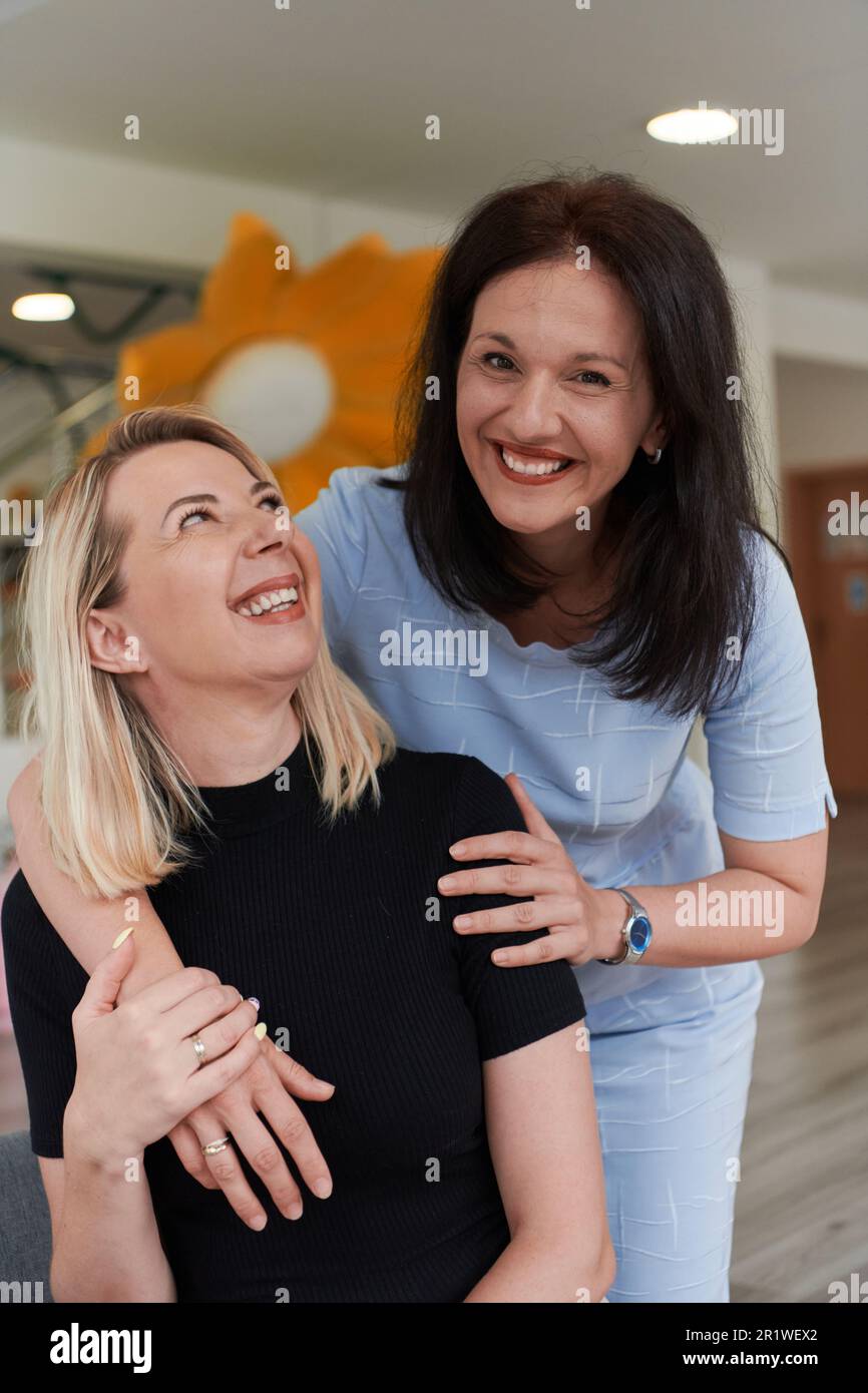Two women share a heartfelt embrace while at a preschool, showcasing ...