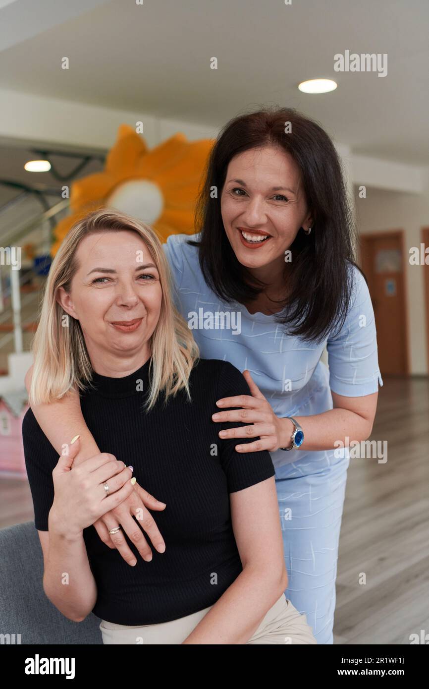 Two women share a heartfelt embrace while at a preschool, showcasing ...