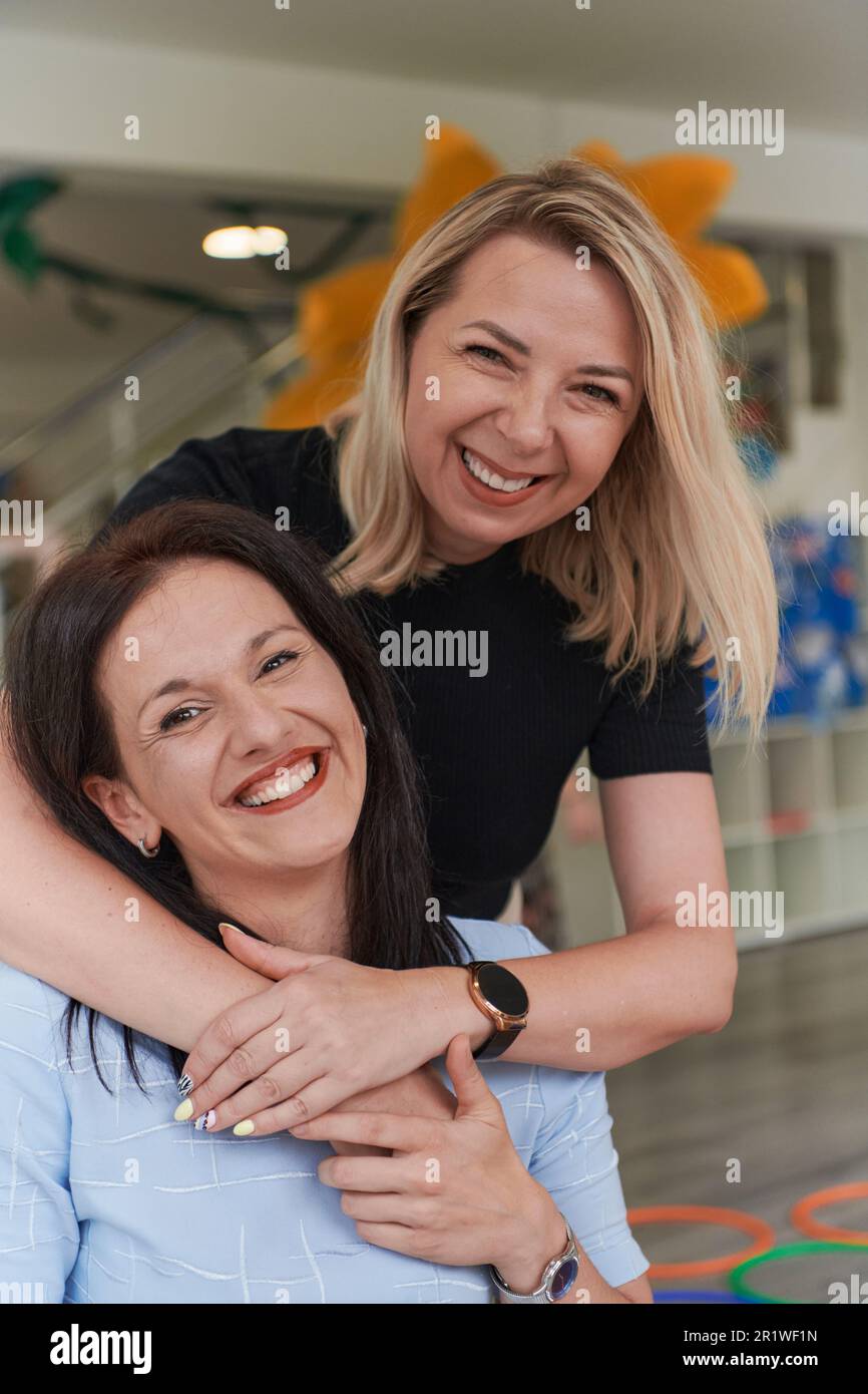 Two women share a heartfelt embrace while at a preschool, showcasing ...
