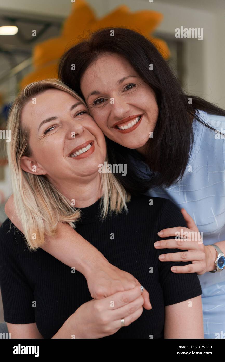 Two women share a heartfelt embrace while at a preschool, showcasing ...