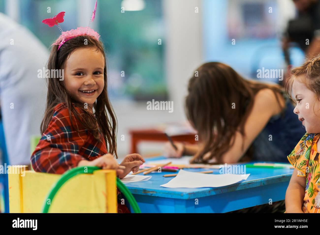 Creative kids during an art class in a daycare center or elementary school classroom drawing ...