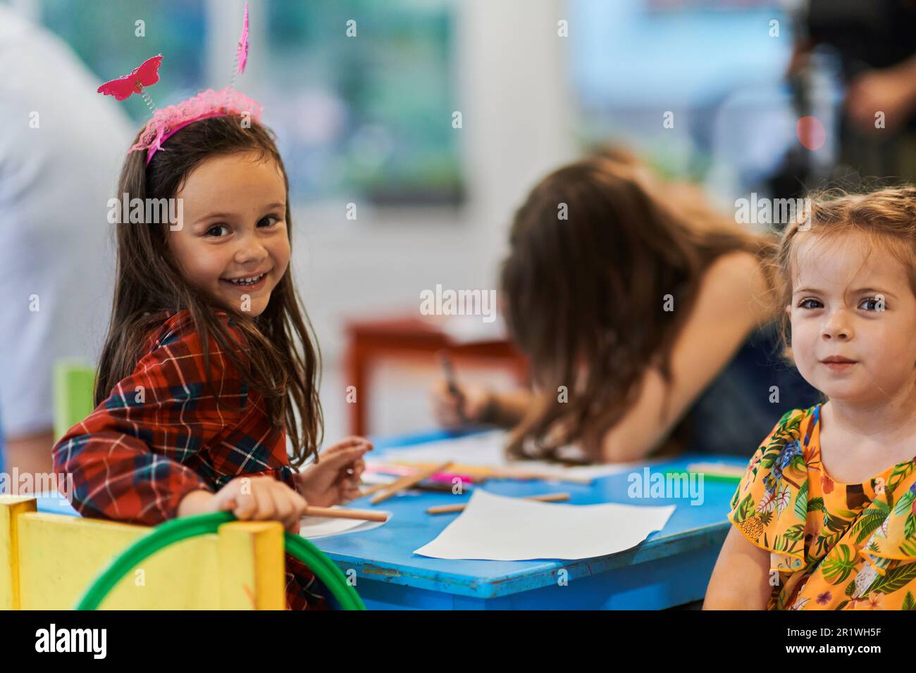 Creative kids during an art class in a daycare center or elementary school classroom drawing ...