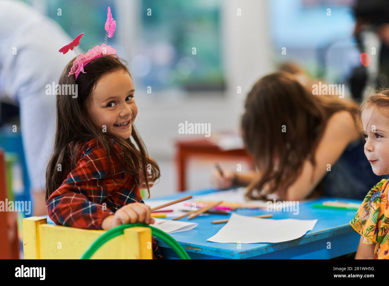 Creative kids during an art class in a daycare center or elementary school classroom drawing ...