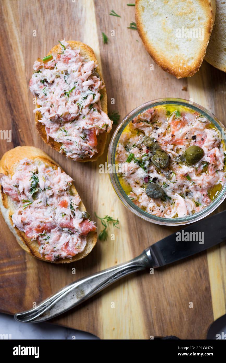 Salmon rillettes, mousse, pate and toasts on wooden background. Bowl of ...