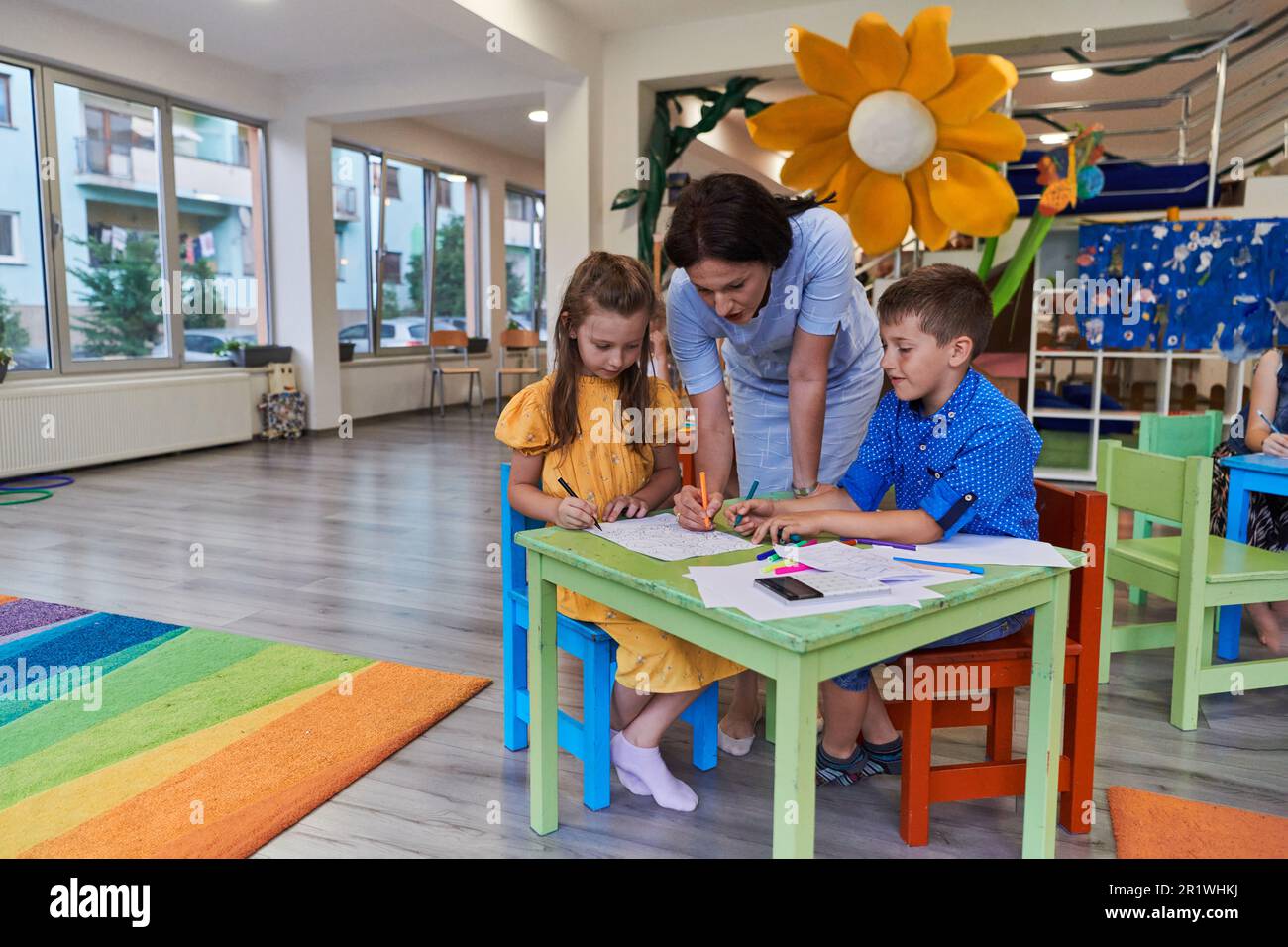 Creative kids during an art class in a daycare center or elementary school classroom drawing ...