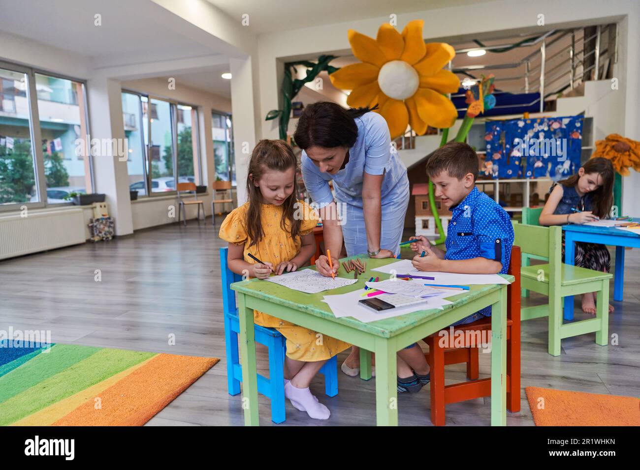 Creative kids during an art class in a daycare center or elementary school classroom drawing ...